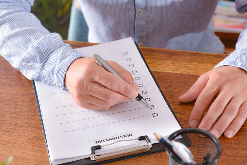 Man Filling Out a Questionnaire on a Wooden Table Front Stock Image ...