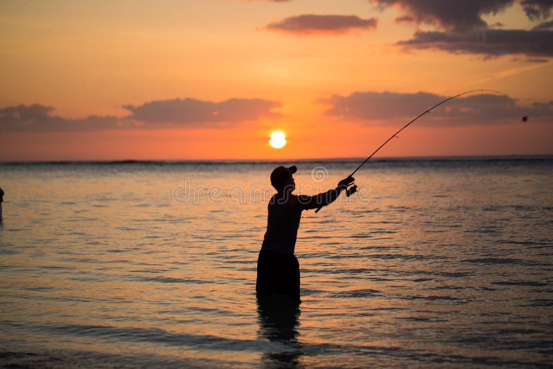 A Man Fishing in the Indian Ocean with the Beach at Sunset. Stock Photo ...