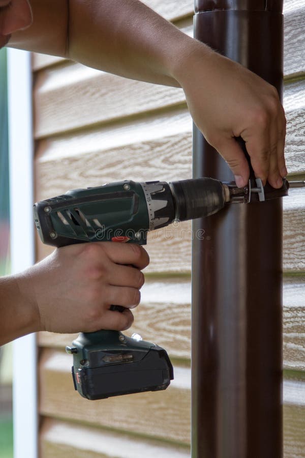 Man Fixes Drain Tube To Wall with Electric Screwdriver Stock Photo ...