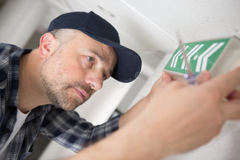 Man Fixing Illuminated Exit Sign To Wall Stock Image - Image of ...