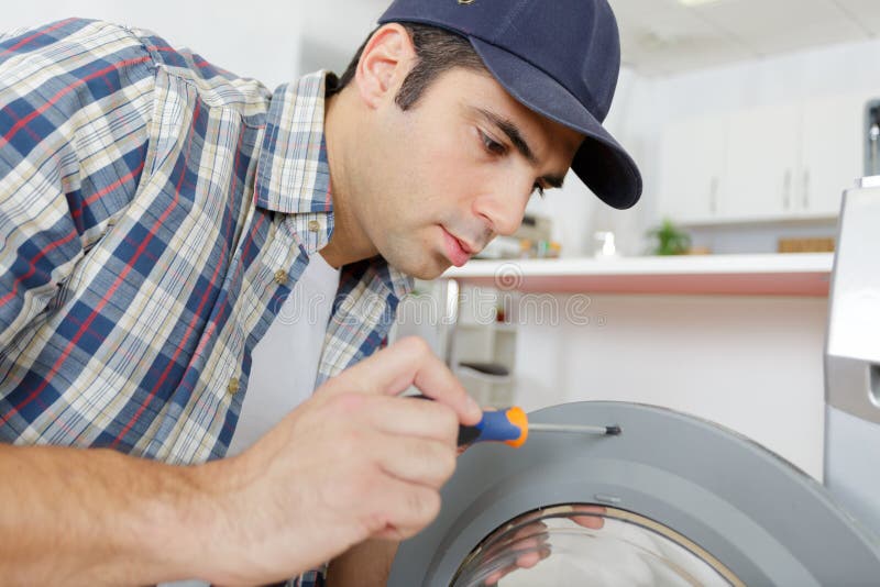Man fixing washing machine stock photo. Image of tool - 161227632