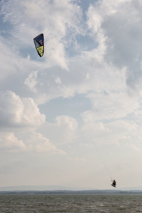 A Man Flying with a Kite Surf on a Lake, with a Deep, Cloudy Sky ...