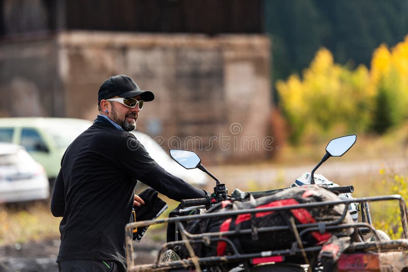 A Man in a Forest Posing Next To a Quad and Preparing for Ride Stock ...