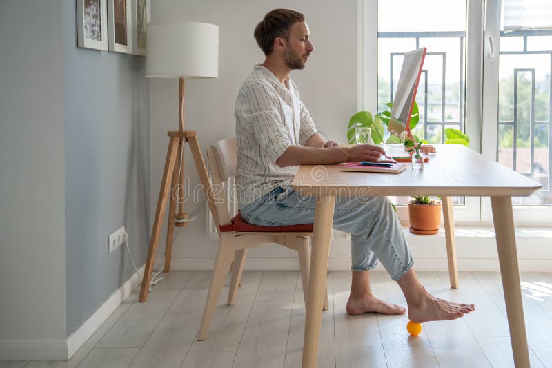 Man Freelancer Working on Computer at Home Doing Recovery Foot Exercise ...