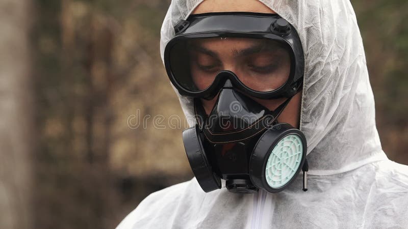 Man in Gas-mask and Bio-hazard Suit Looks Down Taking Notes on His ...