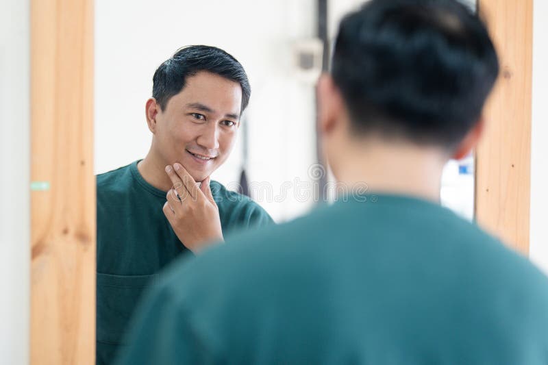 A Man is Observing His Own Face Reflected in a Mirror Thoughtfully ...