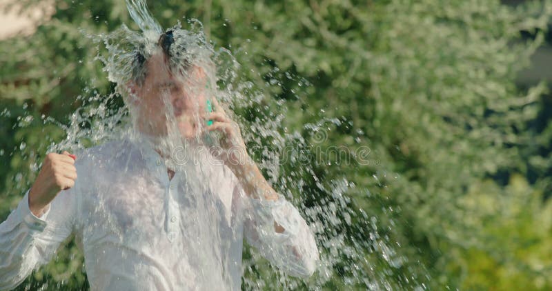 A Man Getting Splashed with Water while Talking on the Phone Stock ...