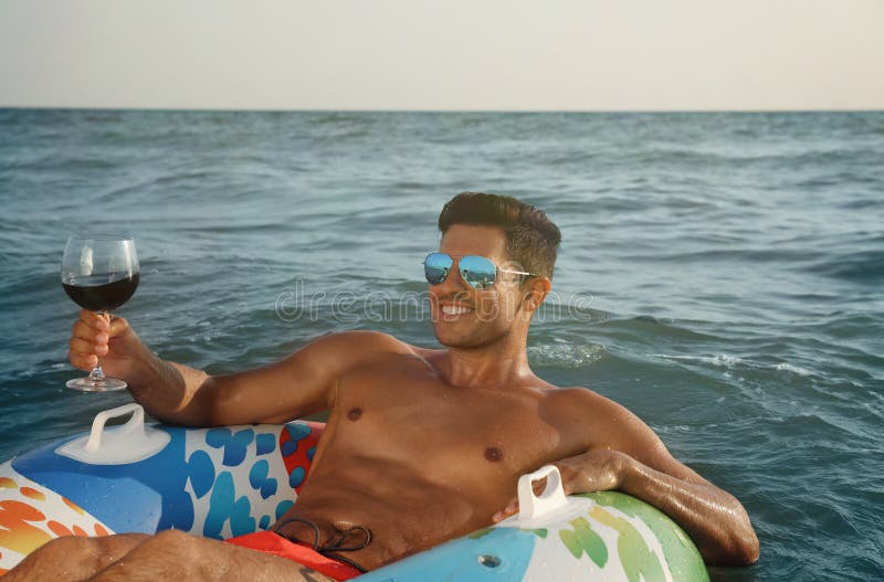 Man with Glass of Wine and Inflatable Ring Resting in Sea Stock Image ...