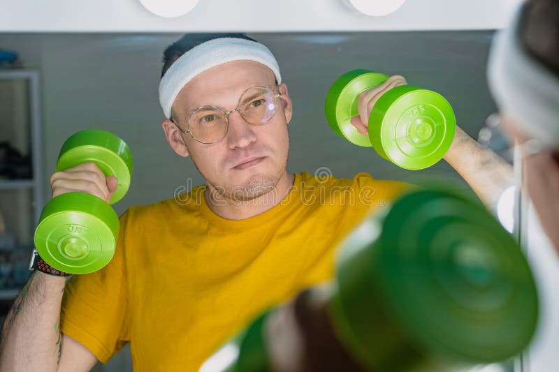 A Man with Glasses and a Headband is Lifting Green Dumbbells while ...