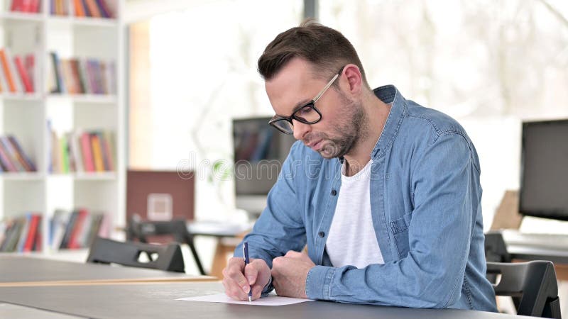 Young Man in Glasses Writing on Paper Stock Photo - Image of contract ...