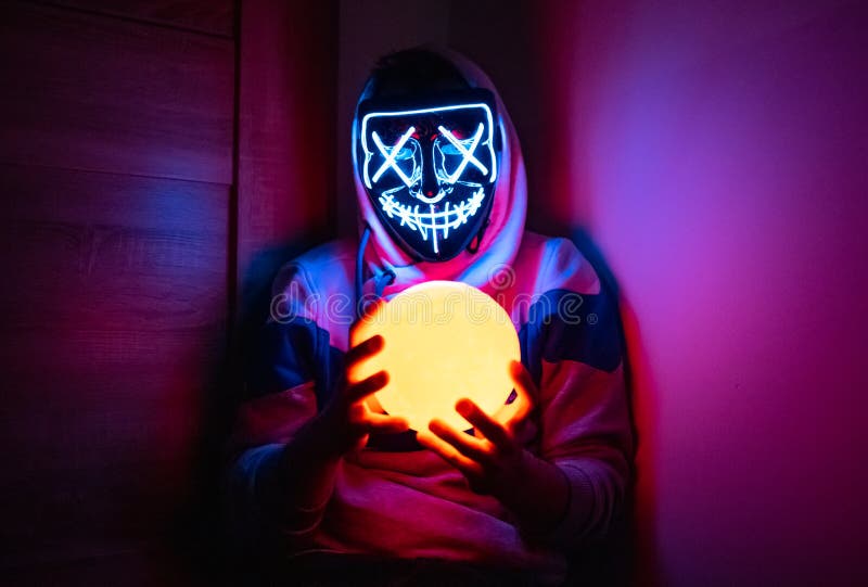 Man in Glowing Mask Sitting in the Corner with Book-shaped Lamp Stock ...
