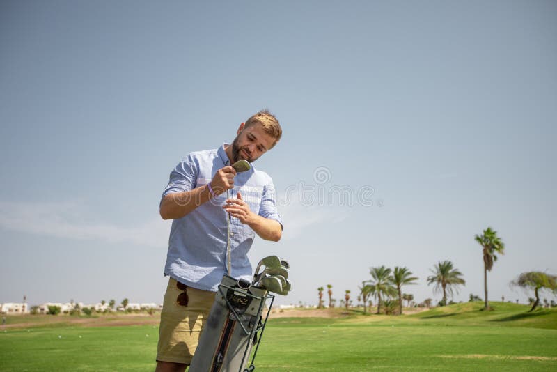 A Man on a Golf Course Examines the Equipment and Prepares for a ...