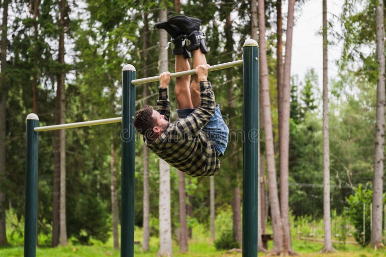 A Man in Gravity Boots Hangs on a Horizontal Bar Outdoors on a Summer ...