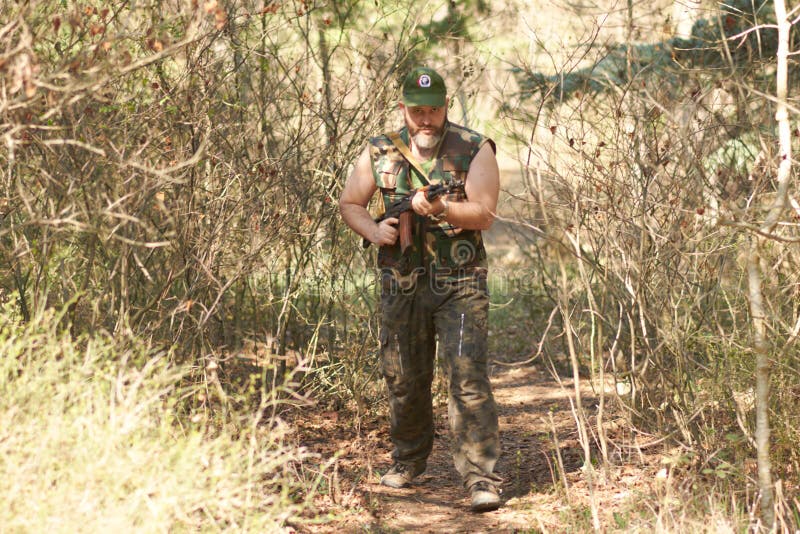 A Man with a Gun in a Forest Stock Photo - Image of backpack, aiming ...