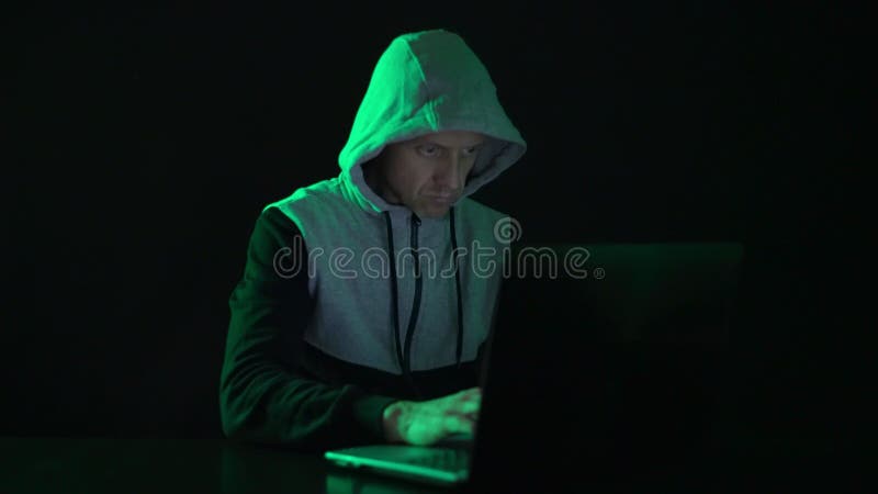 Man a Hacker in the Hood, at the Computer, Looks at the Monitor and ...