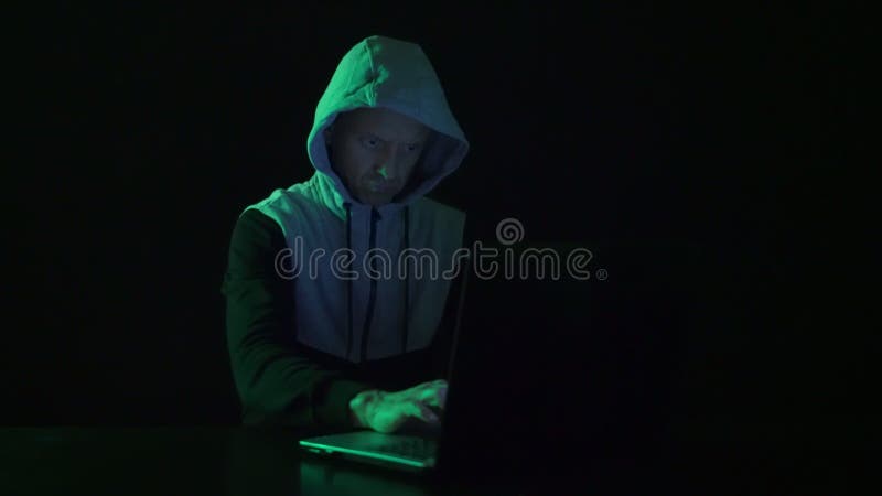 Man a Hacker in the Hood, at the Computer, Looks at the Monitor and ...