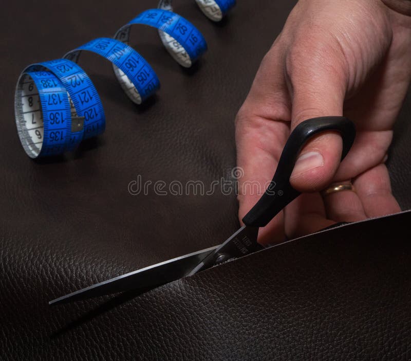 Man Hand Cutting Leather Using Scissors and Twisted Blue Tape Measure ...