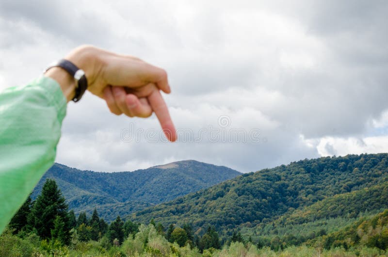 Man Hand in a Green Jacket with Watch Points a Finger To the Top of the ...