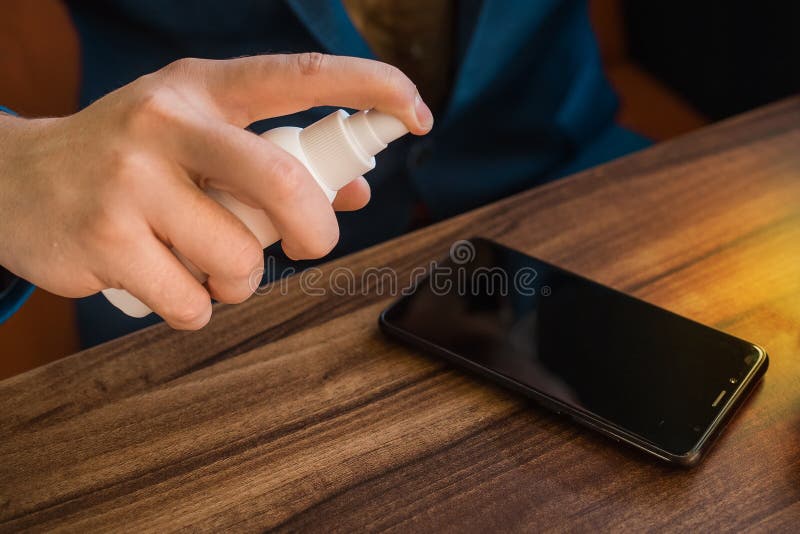 Man Hand Hold Antiseptic and Spray on Phone Screen on Table Background ...