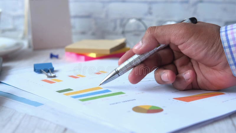 Side View of Man Hand with Pen Analyzing Bar Chart on Paper Stock ...