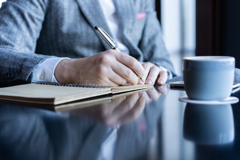 Man Hand with Pen Writing on Notebook on Table. Man Working at Coffee ...