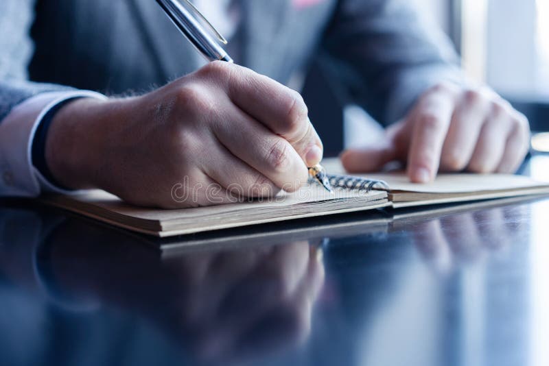 Man Hand with Pen Writing on Notebook on Table. Man Working at Coffee ...