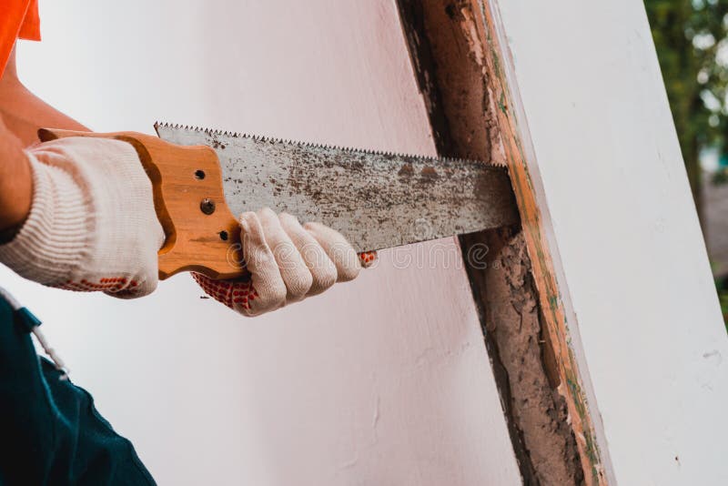 The Man with a Hand Saw Cuts the Mounting Wool Around the Window Frame ...
