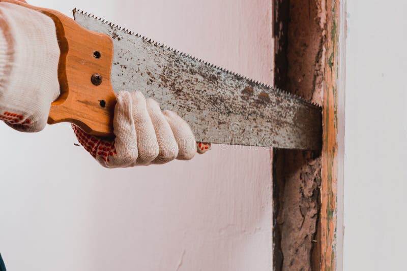 The Man with a Hand Saw Cuts the Mounting Wool Around the Window Frame ...