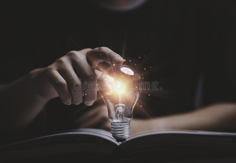 Man Hand Touching To Glowing Lightbulb on Open Book for Reading To ...