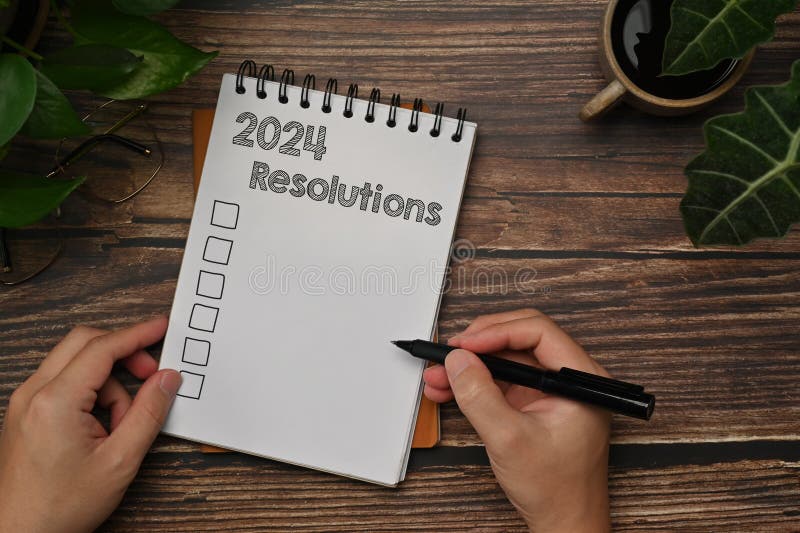 Man Hand Writing in Notebook with List of 2024 Resolutions on Wooden ...