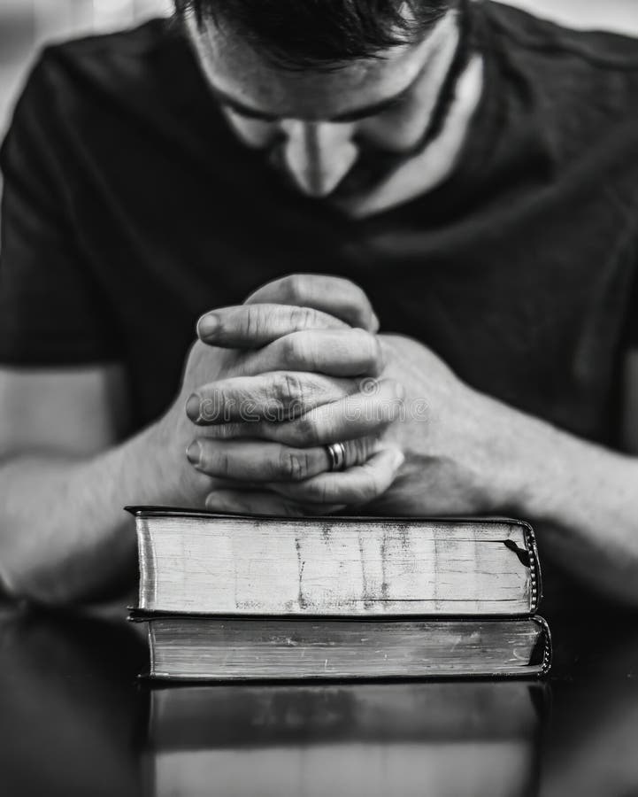 Man With Hands Folded In Prayer On Top Of Bible Head Bowed In Humility