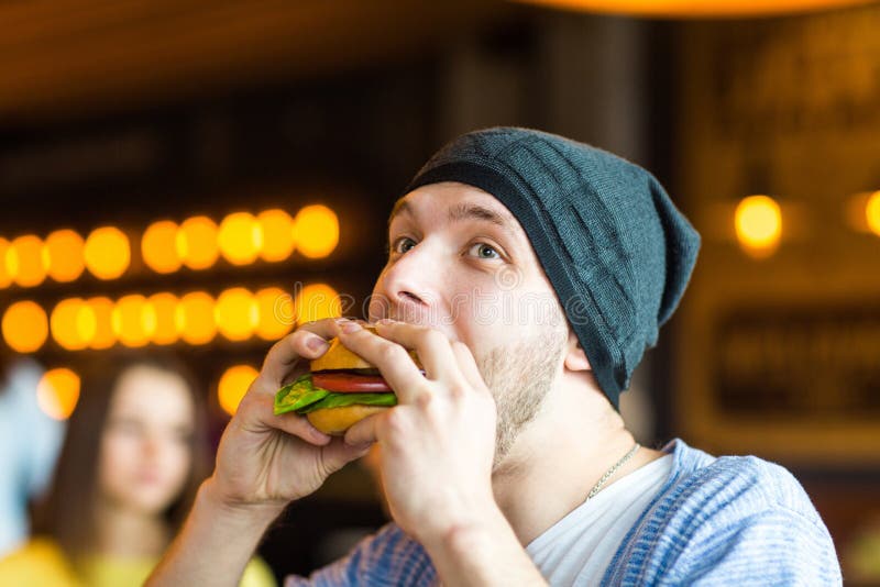 Man in Hands Holds a Burger. Man Eating a Burger at the Cafe Stock ...
