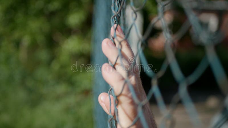 Desperate Man Hands Hanging on a Metallic Fence Inside a Prison ...
