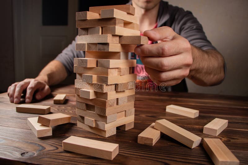 Man Hands Making Stack of Wooden Blocks for Game on Dark Brown Table ...
