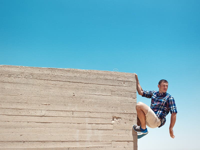 Man hanging on cement wall stock photo. Image of peak - 88556742