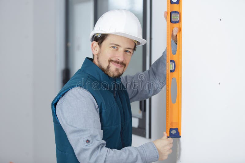 Man with Hard Hat on Construction Site Measuring with Spirit-level ...