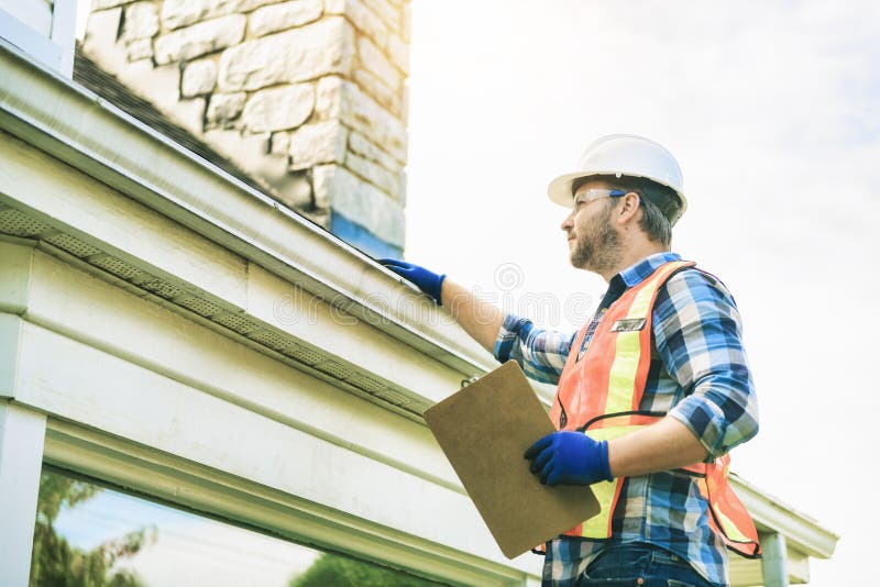 Man with Hard Hat Standing on Steps Inspecting House Roof Stock Photo ...