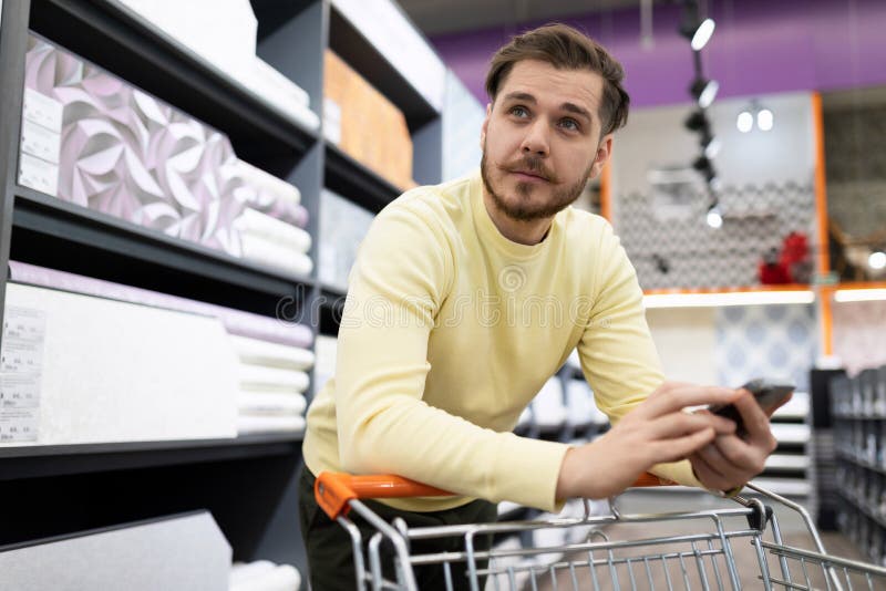 A Man in a Hardware Store Chooses Decorative Wallpaper for the Walls ...