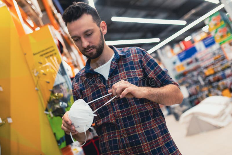 A Man in a Hardware Store Chooses a Protective Mask for Painting Work ...