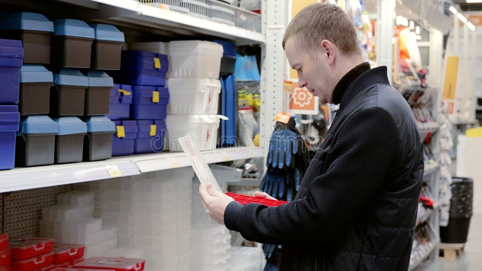 A Man in a Hardware Store Choosing a Toolbox. Customer Comparing ...