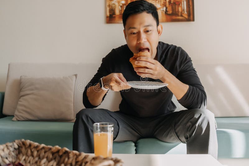 Man Having Bread and Juice As Breakfast on the Sofa Living Room. Stock ...