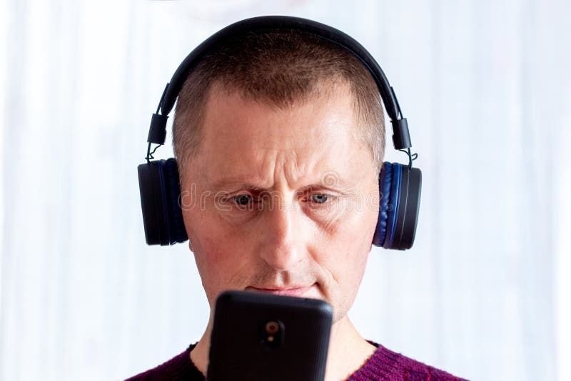 The Man in Headphones Looks at the Phone Stock Image - Image of connect ...