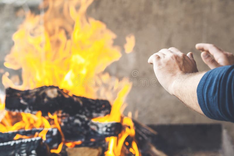 The Man is Heating His Hands by the Fire. Stock Photo - Image of ...