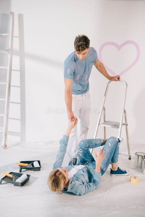 Man Helping Girlfriend Fallen from Ladder and Lying on Floor Stock ...