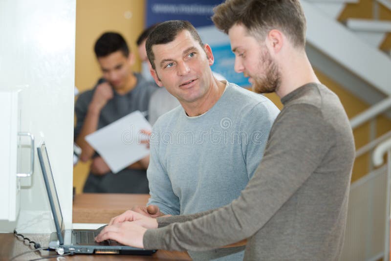 Man Helping Young Man Using Laptop Stock Image - Image of standing ...