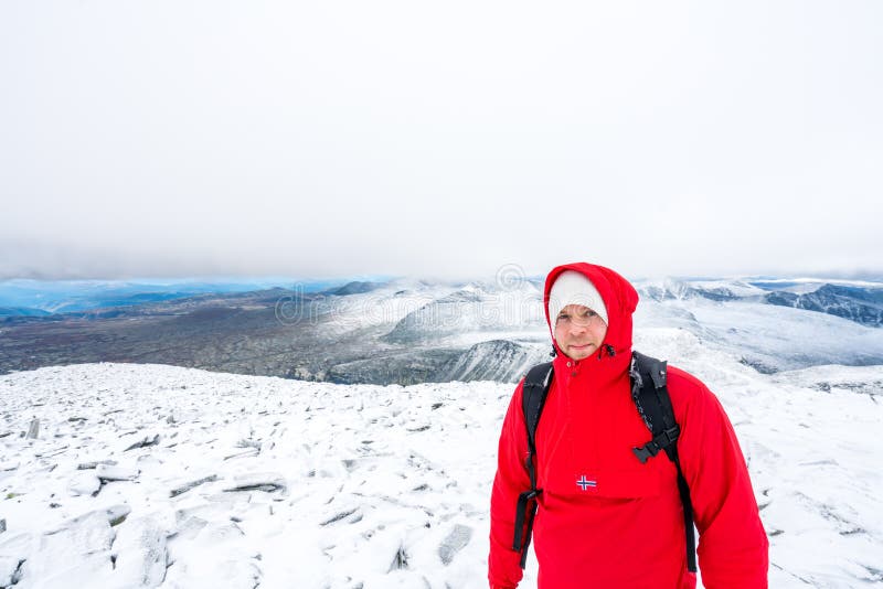 A Man/hiker with Red Jacket and Norwegian Flag on His Chest Standing on ... A Man/hiker with Red Jacket and Norwegian Flag on His Chest Standing on ...