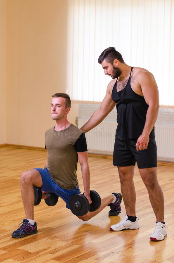 Man and His Personal Trainer Exercising with Dumbbells at the Gym ...