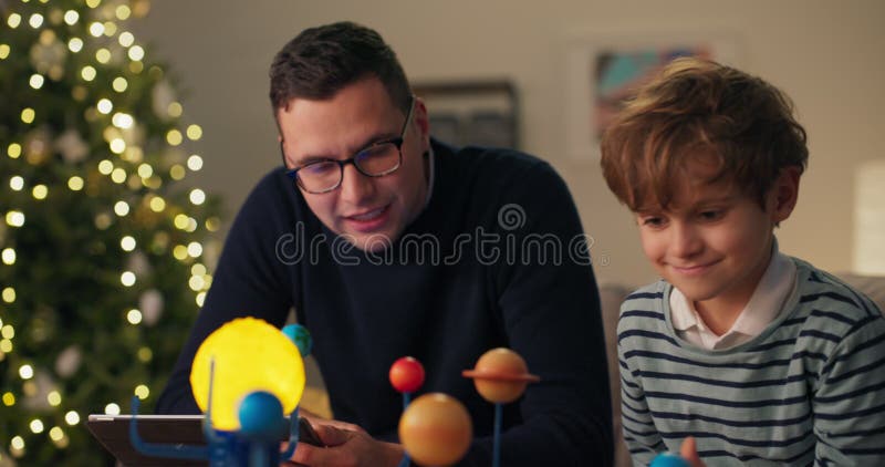 A Man and His Son Assemble a Planetary Model during Christmas Evening ...