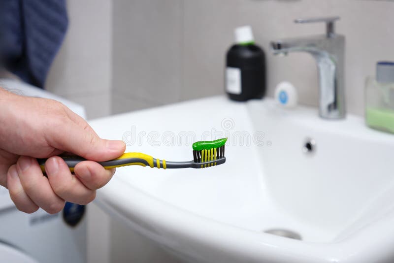 A Man Hold Toothbrush with Green Toothpaste for Teeth in the Bathroom ...