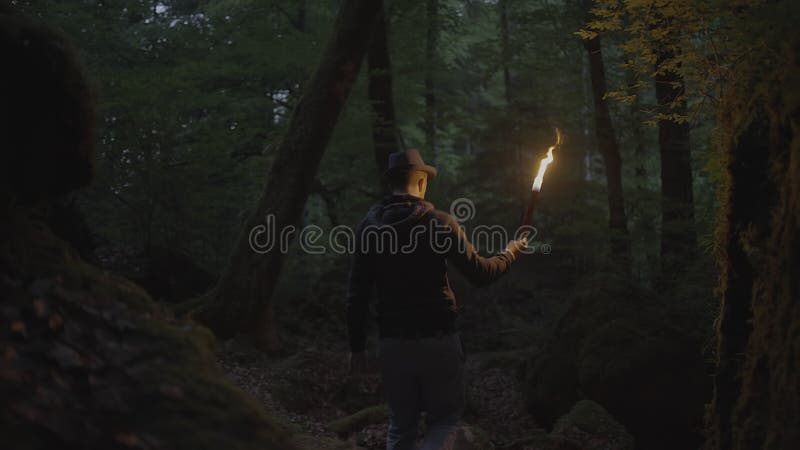 Man Holding a Burning Torchlight Exploring Forest Cave Landscape in ...